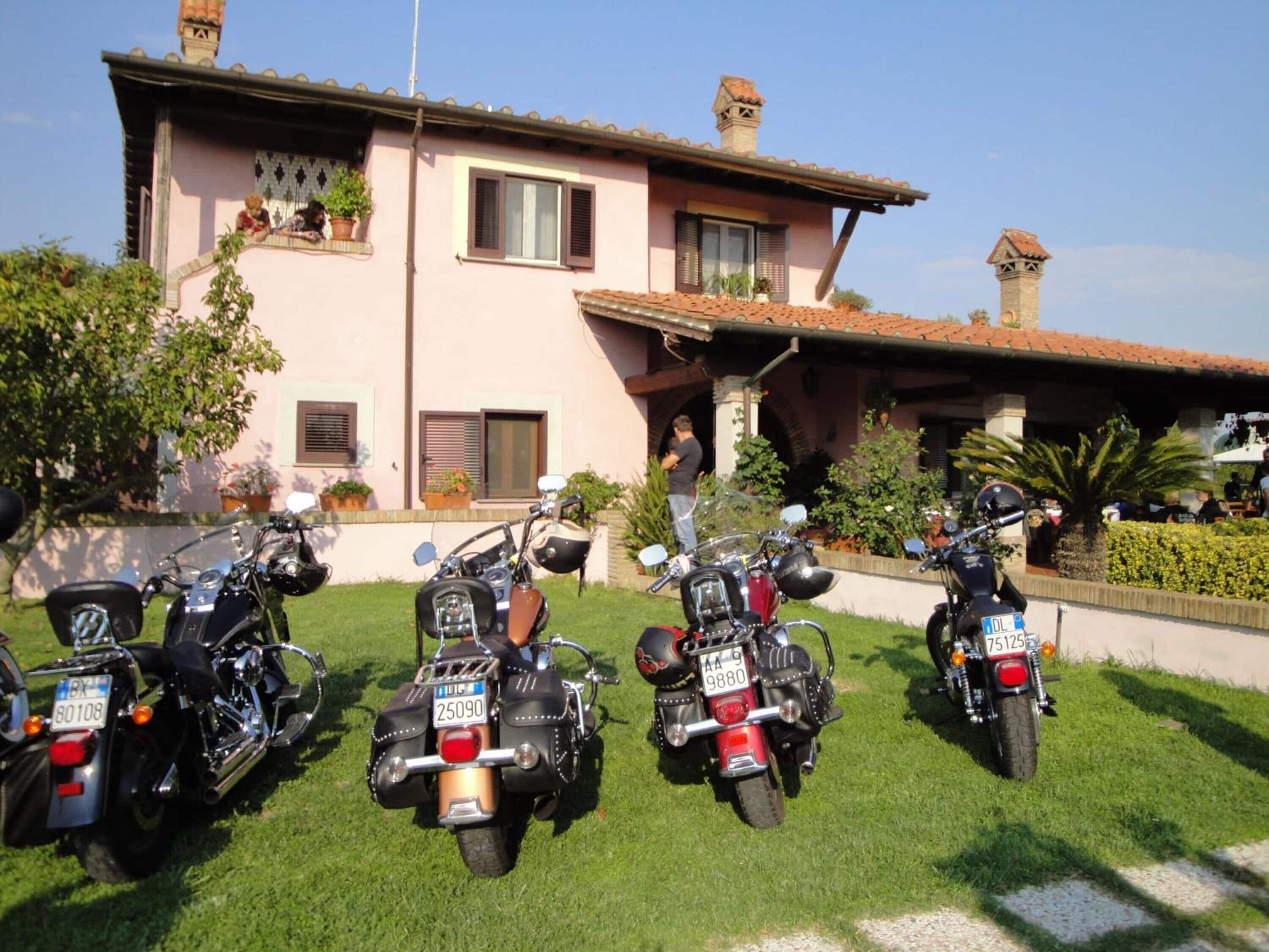 Uma fileira de motocicletas estacionadas em frente a uma casa com telhado de cerâmica e chaminé.