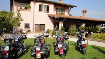 Uma fileira de motocicletas estacionadas em frente a uma casa com telhado de cerâmica e chaminé.