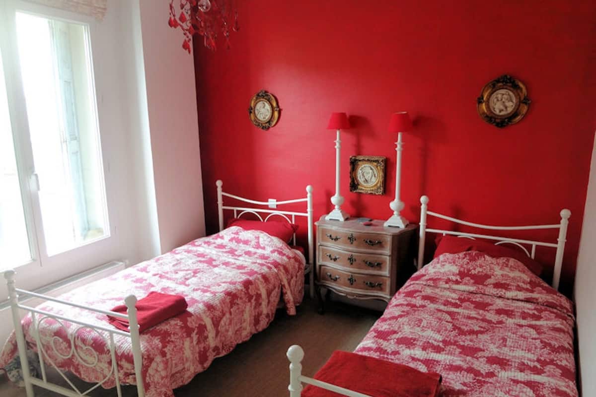 Quarto com duas camas, cômoda e duas horas de parede.
