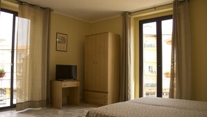 Quarto com cama, escrivaninha, guarda-roupa e televisão.