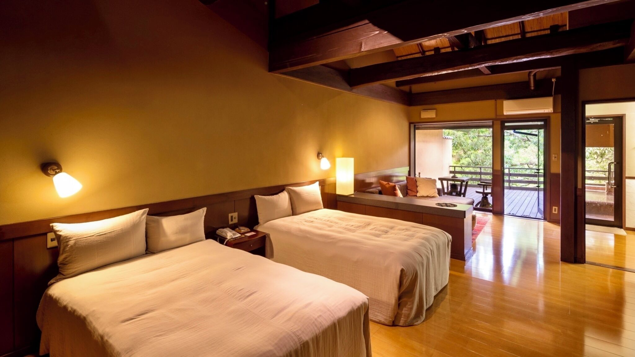 Quarto de hotel com duas camas, um espaço de estar pequeno e vista para o exterior.