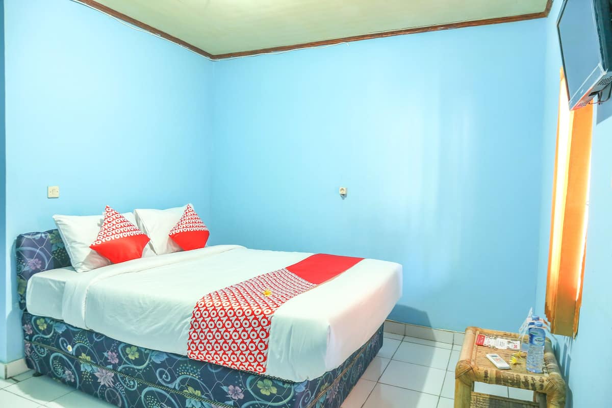 Quarto com cama, almofadas, mesa de cabeceira e ar condicionado fixado na parede.
