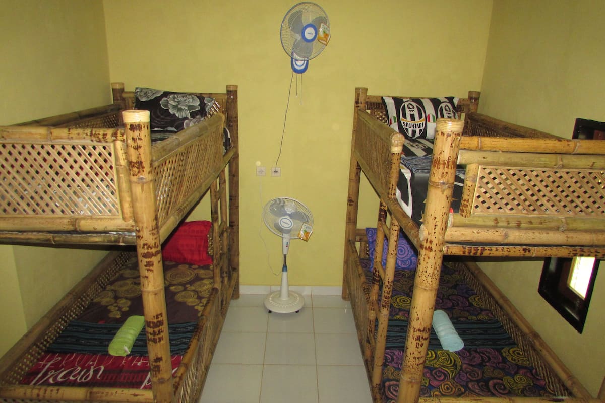 Um quarto com duas beliches, um ventilador e um tapete estampado.