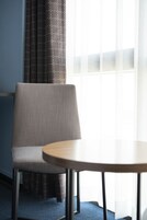 Uma cadeira e uma mesa em um quarto com janela e cortinas.