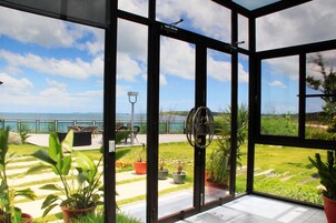 Um solário com vista para uma área gramada e um corpo d'água.