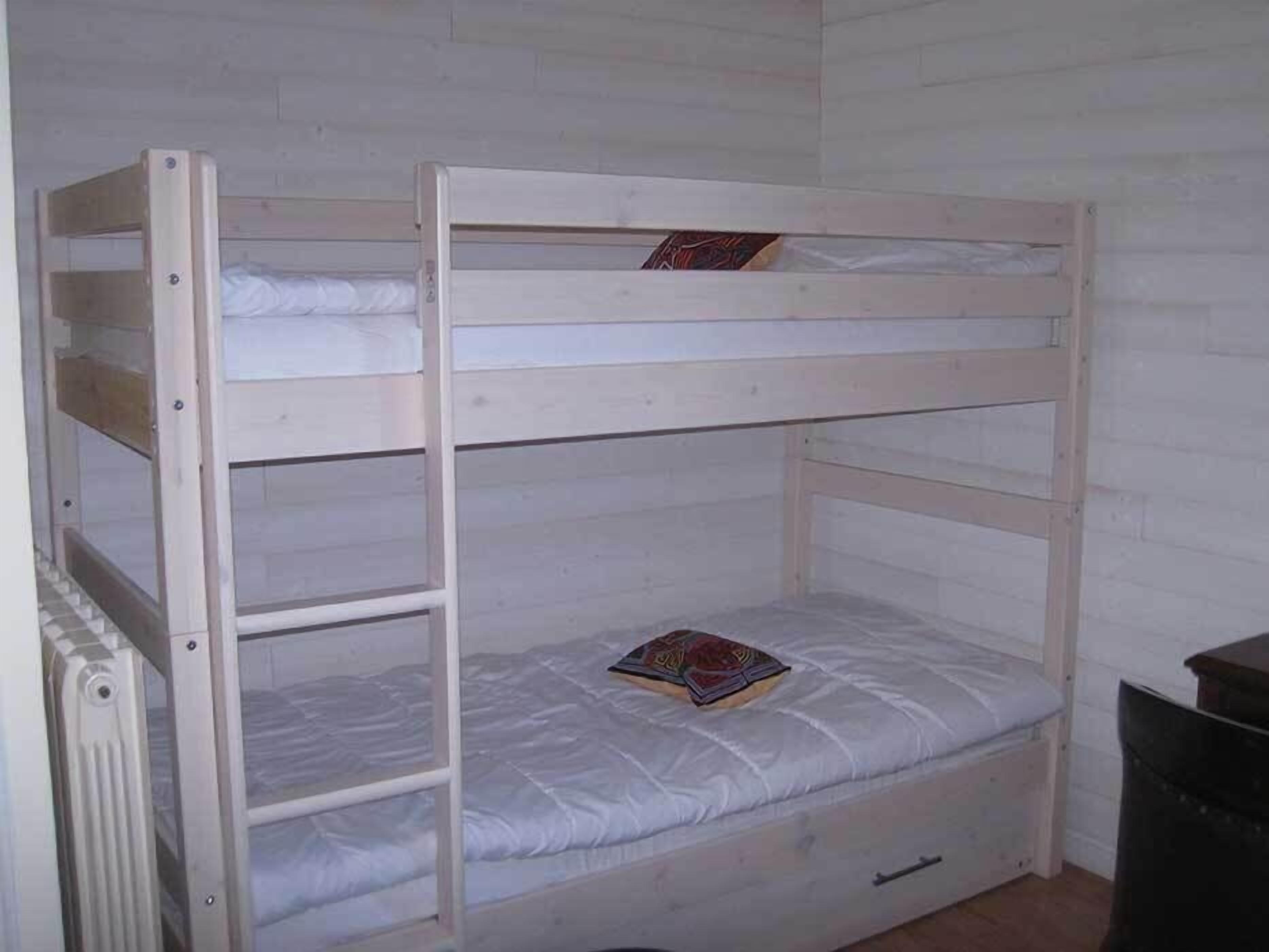 Uma cama beliche com uma cama inferior e uma escrivaninha extensível.