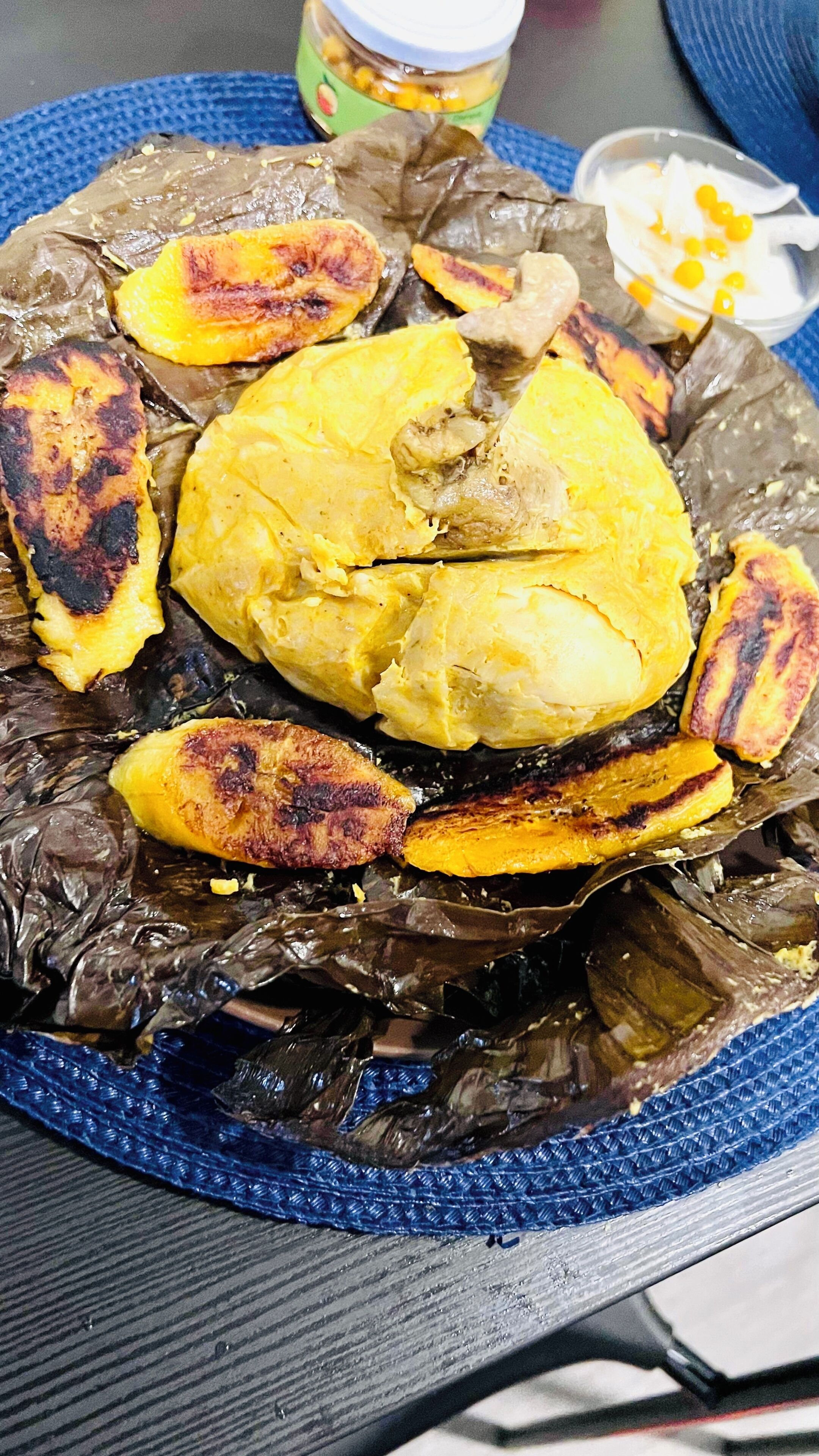 Refeição com carne grelhada e pedaços de fruta amarela sobre um prato trançado.