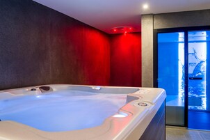 Um spa moderno com banheira de hidromassagem, paredes vermelhas e porta de vidro para área de piscina.