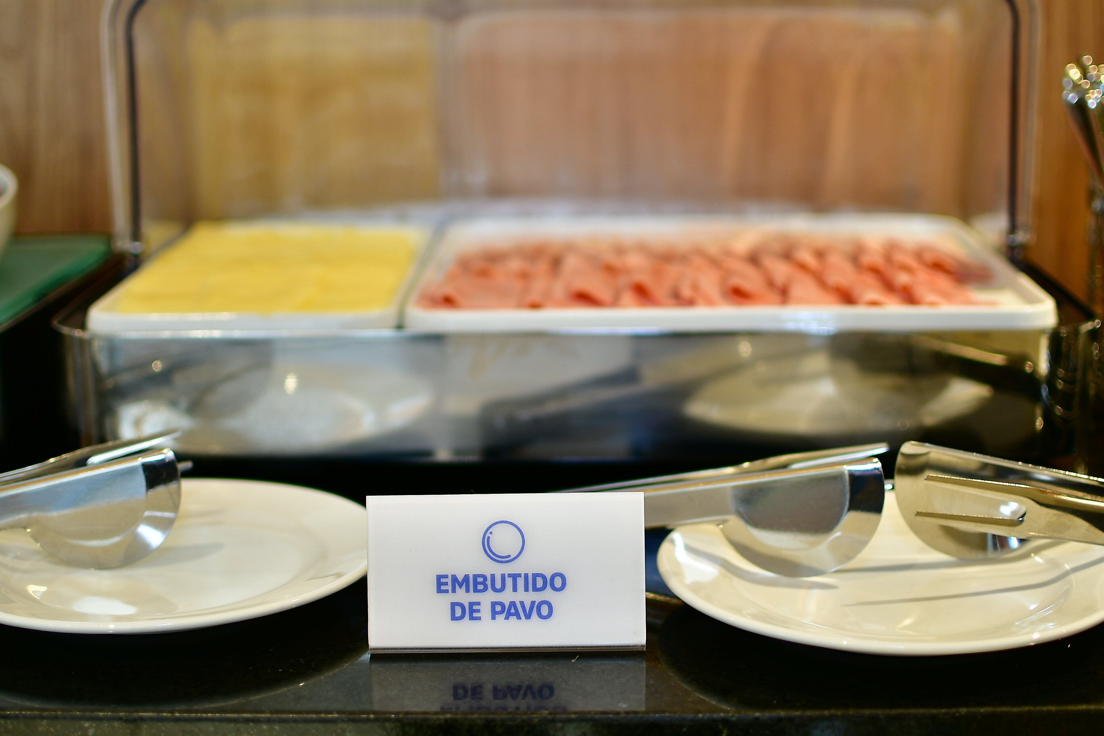 Buffet com seções identificadas para diferentes tipos de comida.