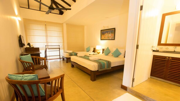 Quarto de hotel com cama, escrivaninha, cadeira e banheiro.