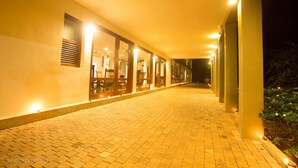 Uma galeria coberta com chão de tijolos, portas de vidro e iluminação acolhedora.