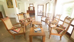 Um quarto amplo com mobiliário de madeira, incluindo cadeiras e uma mesa, e uma janela grande que permite entrada de luz natural.