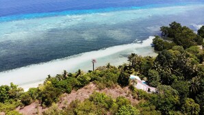 Uma praia com águas turquesa cristalinas, areal arenoso e vegetação tropical exuberante.