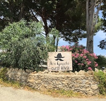 Placa de 'Don Giacchi Guest House' com parede de pedra rústica e vegetação exuberante.