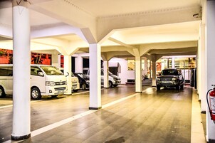 Uma área de estacionamento coberta com vários carros estacionados sob pilares brancos.