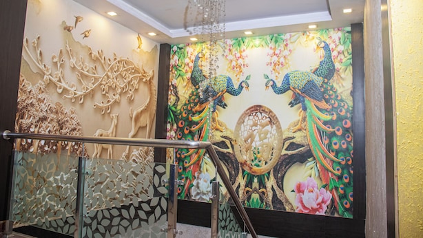 Escadaria com guarda-corpo de vidro, mural de pavão e lustre.