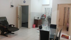 Um espaço de estar compacto com área de refeições, uma cozinha compacta e uma porta visível que dá para outro cômodo.
