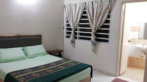Quarto com cama, mesa de cabeceira, janela com cortinas, porta para um banheiro e ar-condicionado fixado na parede.
