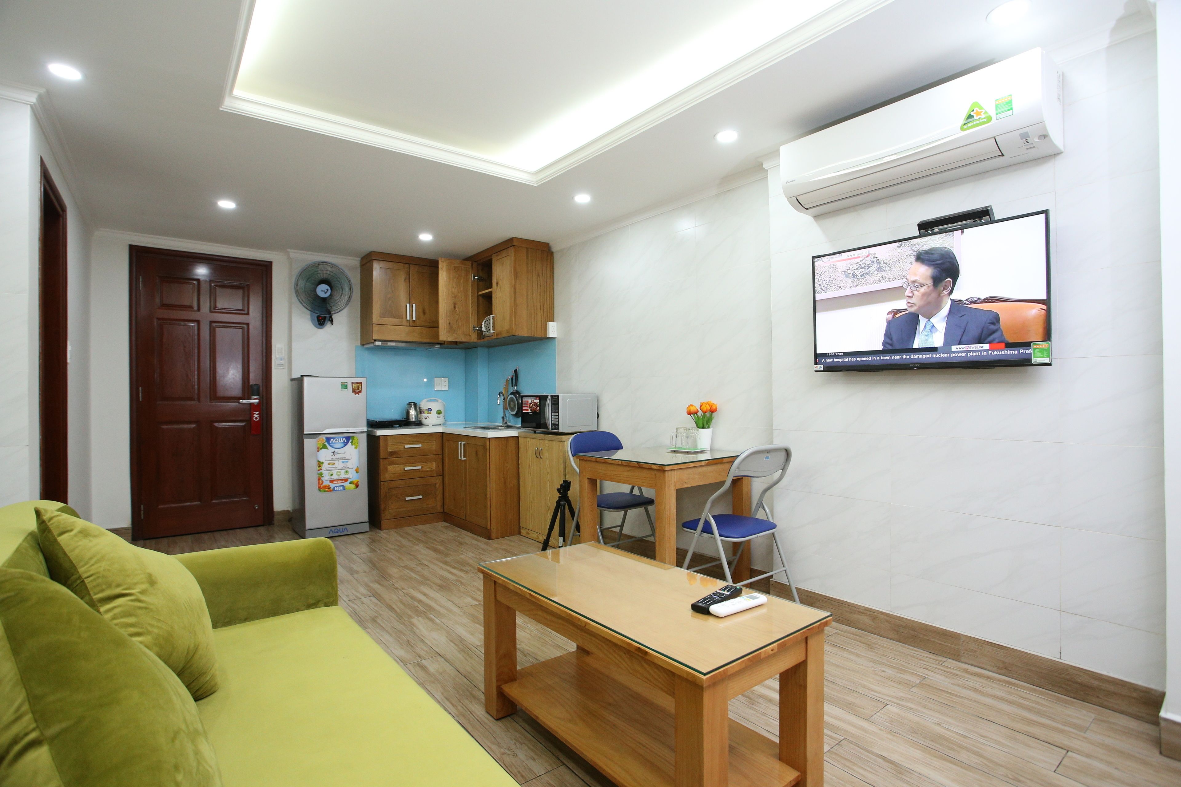 Um espaço compacto com cozinha compacta, área de jantar e televisão fixada na parede.