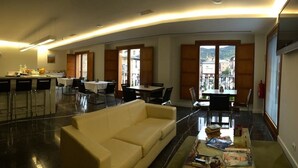 Uma sala ampla com sofá, mesa de jantar e cadeiras. Há uma cozinha com balcão e vista para a cidade.