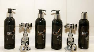 Casa de banho com seis frascos de produtos Rosemary & Bergamot e uma torneira cromada.