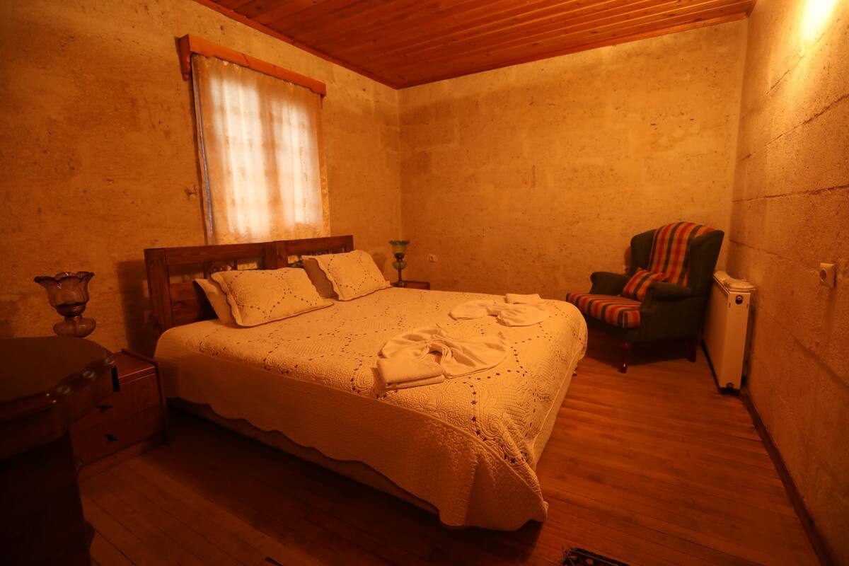 Um quarto acolhedor com uma cama de madeira, uma cadeira e uma mesinha.