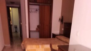 Quarto com uma cama, uma cadeira de madeira e uma escrivaninha.