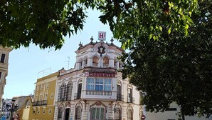 Um edifício histórico com um letreiro 'H' em destaque, provavelmente um hotel, apresentando arquitetura clássica com detalhes ornamentais e uma varanda.