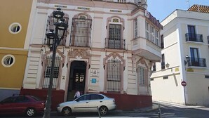 Um edifício histórico com entrada central, uma varanda e uma placa indicando um hotel.