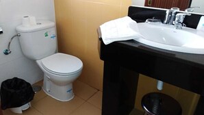 Casa de banho com sanita, lavatório e um caixote de lixo preto.