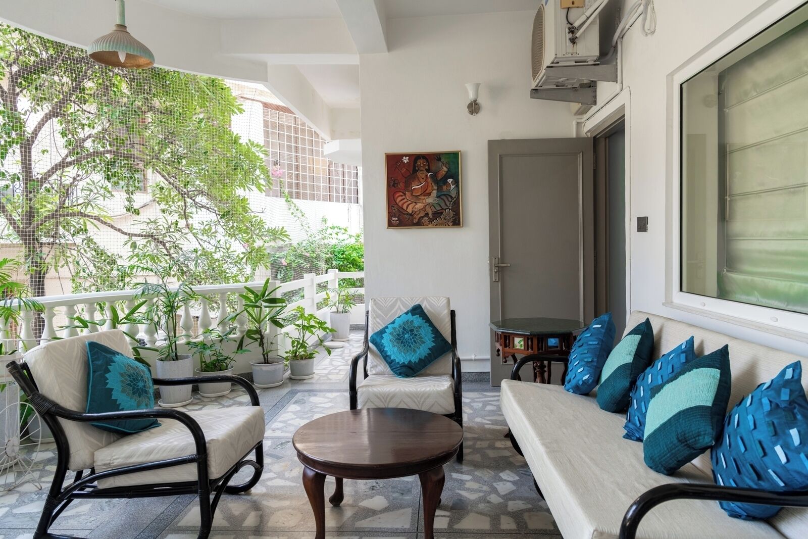 Varanda com mobiliário externo, vasos de plantas e vista para a cidade.