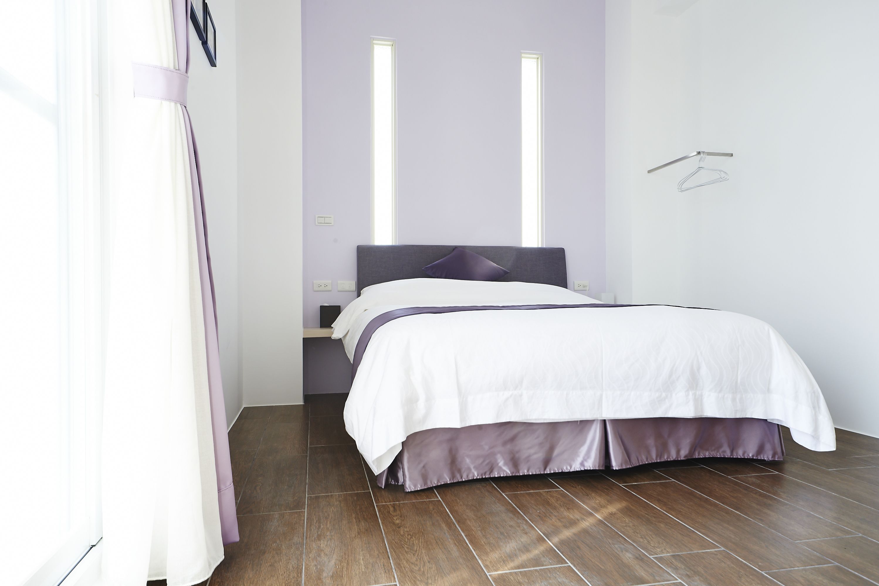 Quarto com cama, mesa de cabeceira e janela com persianas.