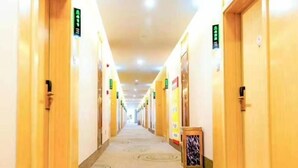 Um corredor de hotel com portas de madeira, carpete estampado e placas de sinalização.