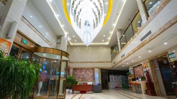 Um hall amplo com um lustre moderno, portas de vidro e um balcão de recepção.
