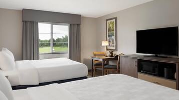 Quarto de hotel com duas camas, uma escrivaninha, televisão e micro-ondas.