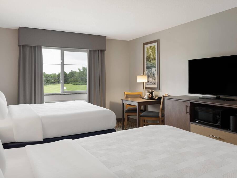 Quarto de hotel com duas camas, uma escrivaninha, televisão e micro-ondas.