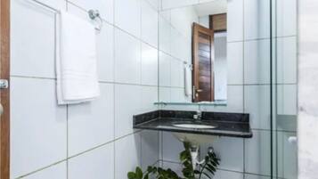 Um banheiro pequeno com azulejos brancos, pia, espelho e um vaso de planta.