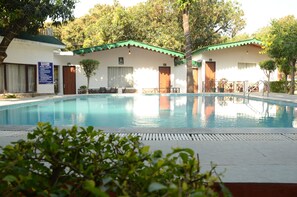 Piscina com vista desobstruída da região circundante, incluindo um edifício com telhado verde e uma placa de identificação.