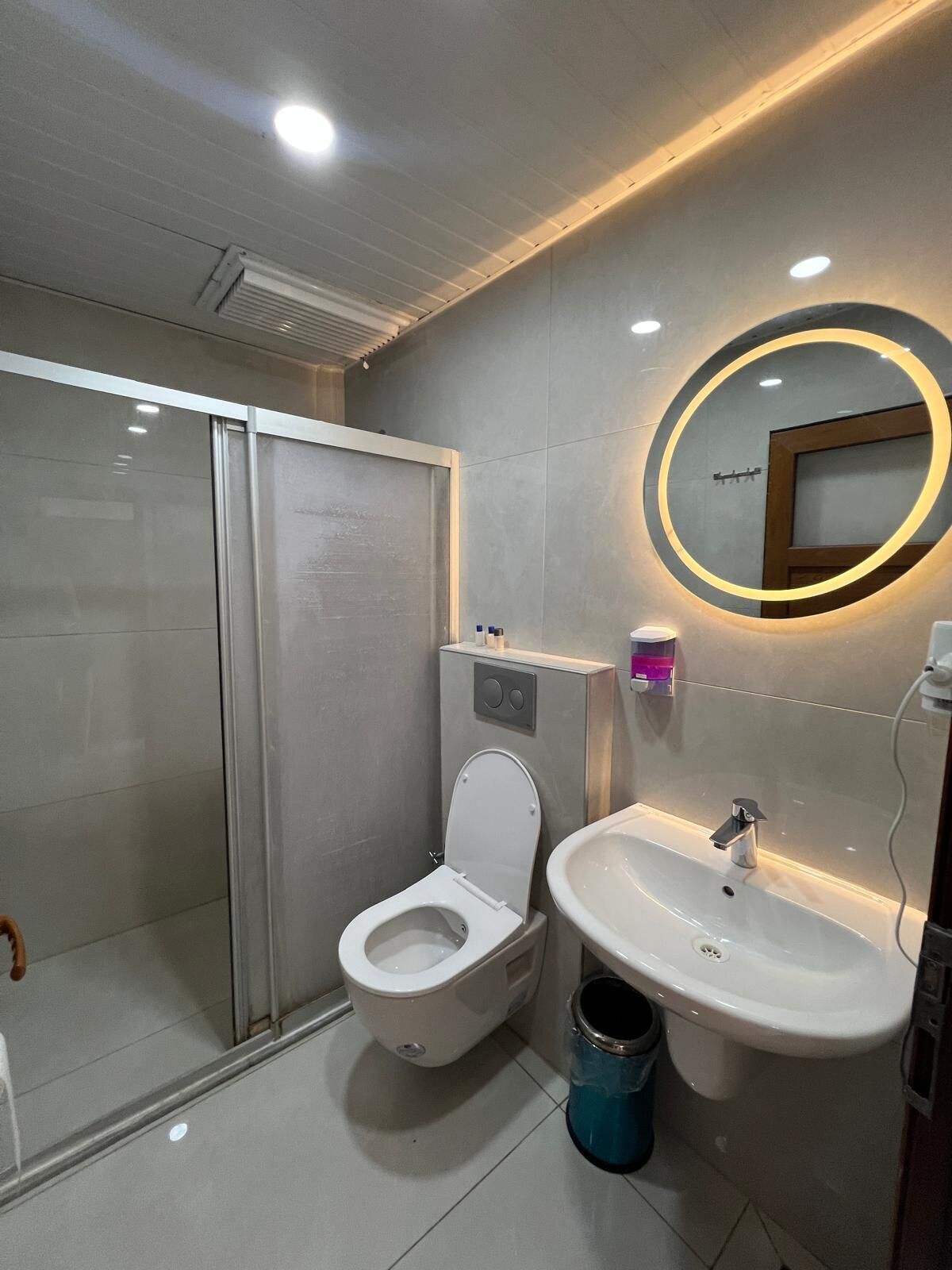 Casa de banho moderna com sanita, lavatório e cabine de duche em vidro.
