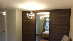 Quarto com porta deslizante, um candelabro, uma cadeira e vista pela porta.