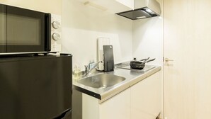 Cozinha compacta com geladeira de aço inoxidável, micro-ondas, pia e fogão.