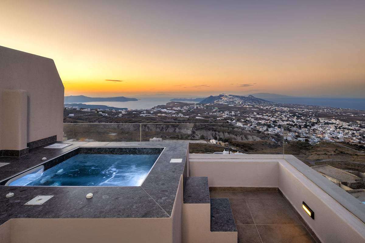 Piscina no terraço com vista para uma cidade costeira ao pôr do sol.