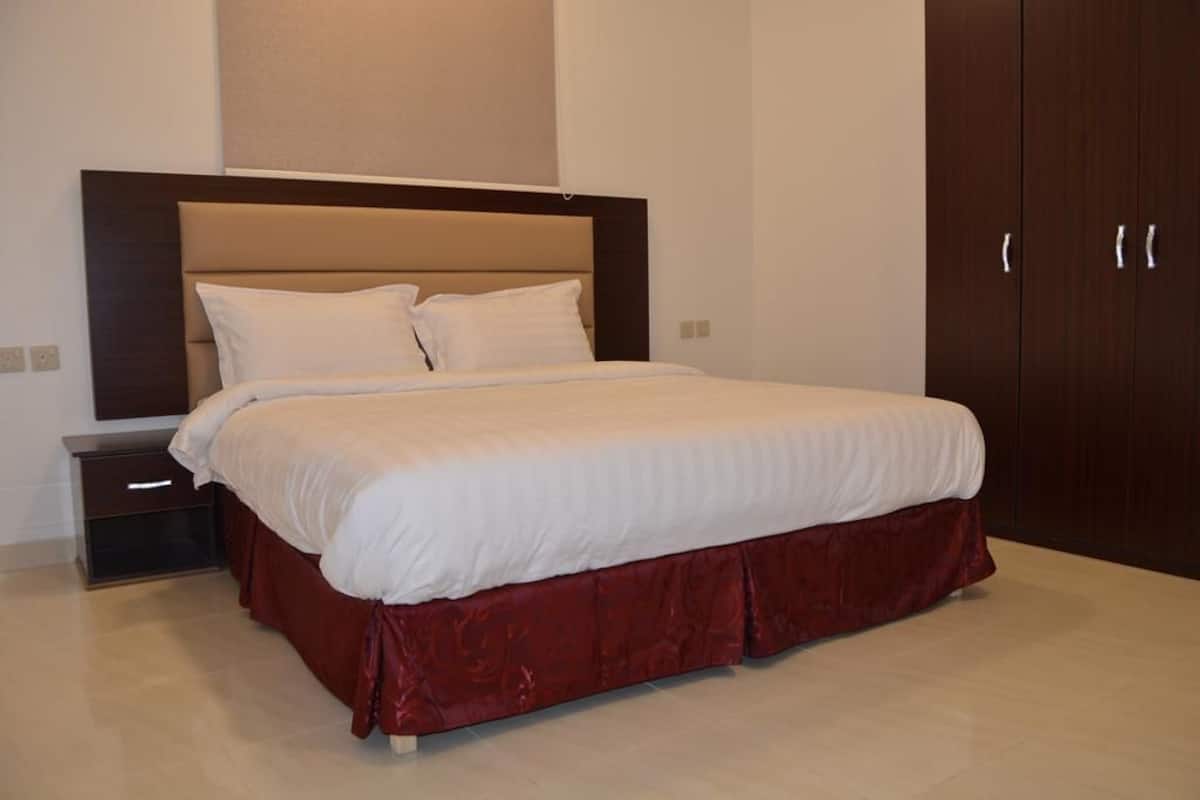 Um quarto com uma cama grande, uma mesa de cabeceira e um guarda-roupa.