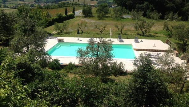 Uma piscina retangular com superfície de água azul cristalina, rodeada por um deck branco.