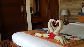 Quarto de hotel com cama bem arrumada, escrivaninha de madeira e guarda-roupa.