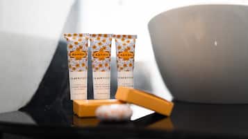 Três frascos de gel de banho Claus Porto e uma tigela sobre uma mesa.