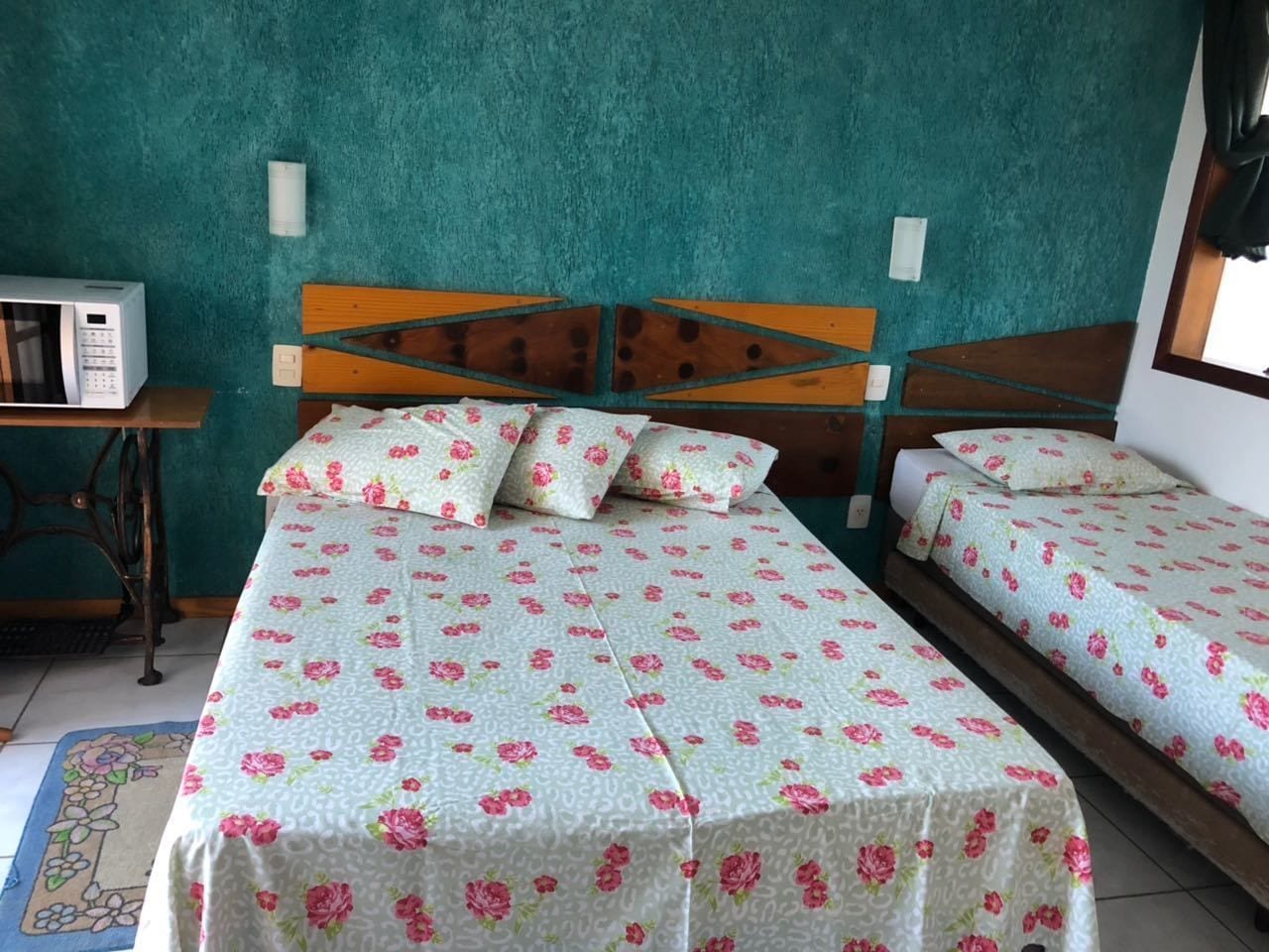 Quarto com duas camas, paredes cor turquesa e cabeceira de madeira.