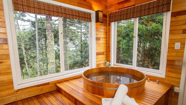 Uma sauna de madeira com uma janela grande, um banco de madeira e uma toalha no banco.