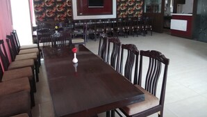 Uma sala de conferência com uma mesa comprida, várias cadeiras, uma tela de projetor e um papel de parede estampado.