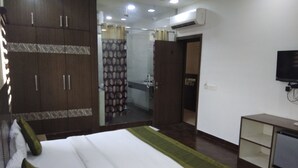 Quarto de hotel com cama grande, escrivaninha, ar condicionado e televisão.